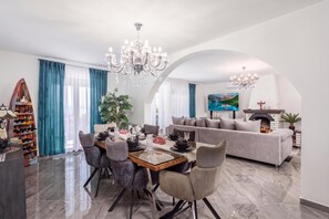 Uma área de refeições com um candelabro, um conjunto de sofás e uma lareira.