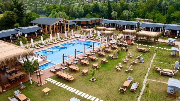 Um resort com piscina central, áreas de estar ao ar livre e construções com telhados de palha.
