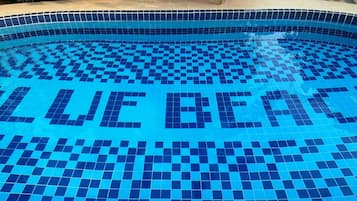 Piscina com padrão de azulejos quadriculados e a inscrição "BLUE BEACH" nos azulejos.