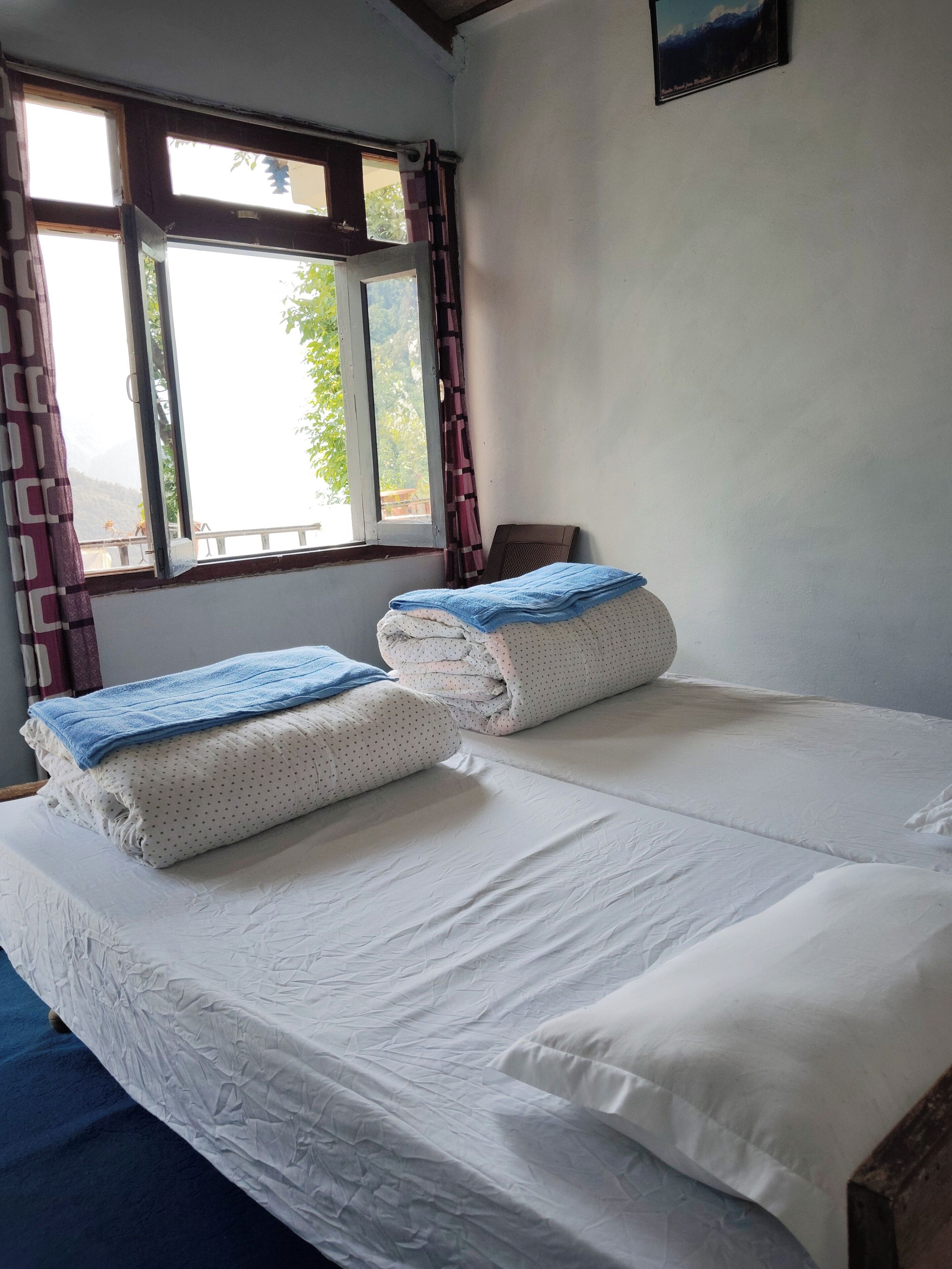 Quarto com duas camas, janela com cortinas e uma cadeira.