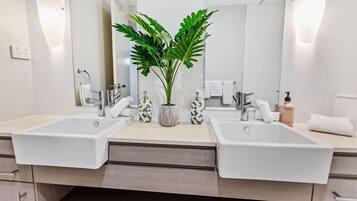 Uma casa de banho moderna com duas pias, um espelho grande e uma planta em vaso.