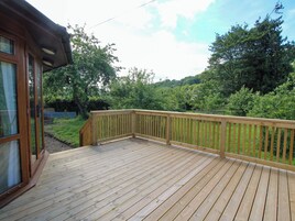 Um deck de madeira com guarda-corpo, cercado por vegetação exuberante e árvores.