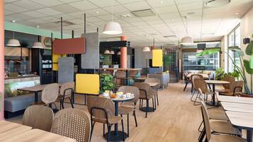 Um restaurante moderno com diversas áreas de estar, incluindo cabines e mesas, e uma variedade de cadeiras.