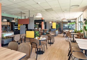 Um restaurante moderno com diversas áreas de estar, incluindo cabines e mesas, e uma variedade de cadeiras.