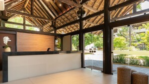 Uma área de recepção com teto de madeira, balcão de atendimento e vista para o exterior.