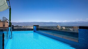 Piscina infinita no terraço, com vista desobstruída para montanhas e horizonte urbano.
