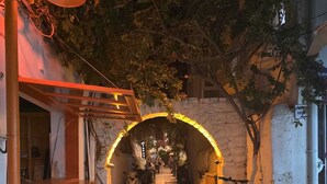 Uma viela estreita com um caminho de pedra, um banco de madeira e uma bicicleta estacionada à direita.