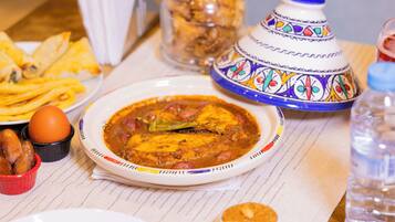 Uma mesa de jantar com diversos pratos, incluindo um prato de peixe, uma tigela de azeitonas e um vaso decorativo.