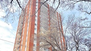 Um edifício residencial de vários andares com fachada de tijolos e diversas varandas.