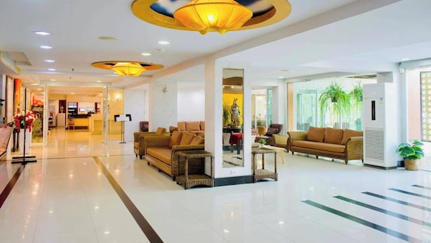 Um hall amplo com teto alto, mobiliário moderno e uma grande janela que permite entrada de luz natural.