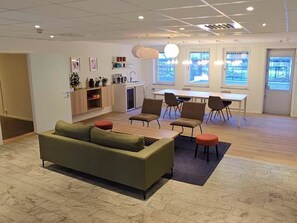 Uma sala de estar moderna com sofá, pufes e um espaço de jantar com cadeiras e mesa.