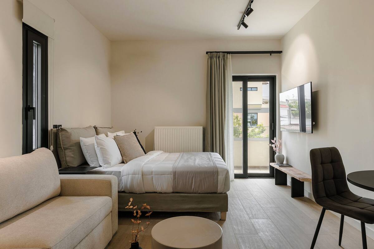 Quarto de hotel moderno com cama, sofá e mesa de centro redonda.