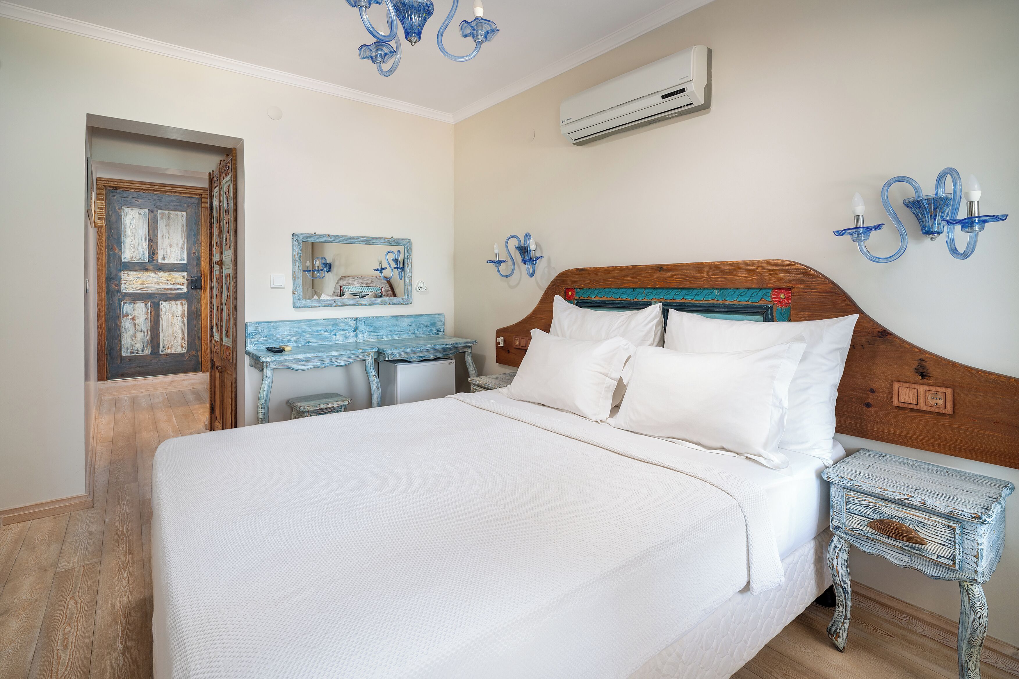 Quarto com cama grande, cabeceira de madeira, mesa de cabeceira pequena e ar condicionado fixado na parede.