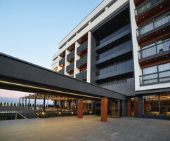 Um hotel moderno de vários andares com área externa coberta, assentos e vista para as montanhas.