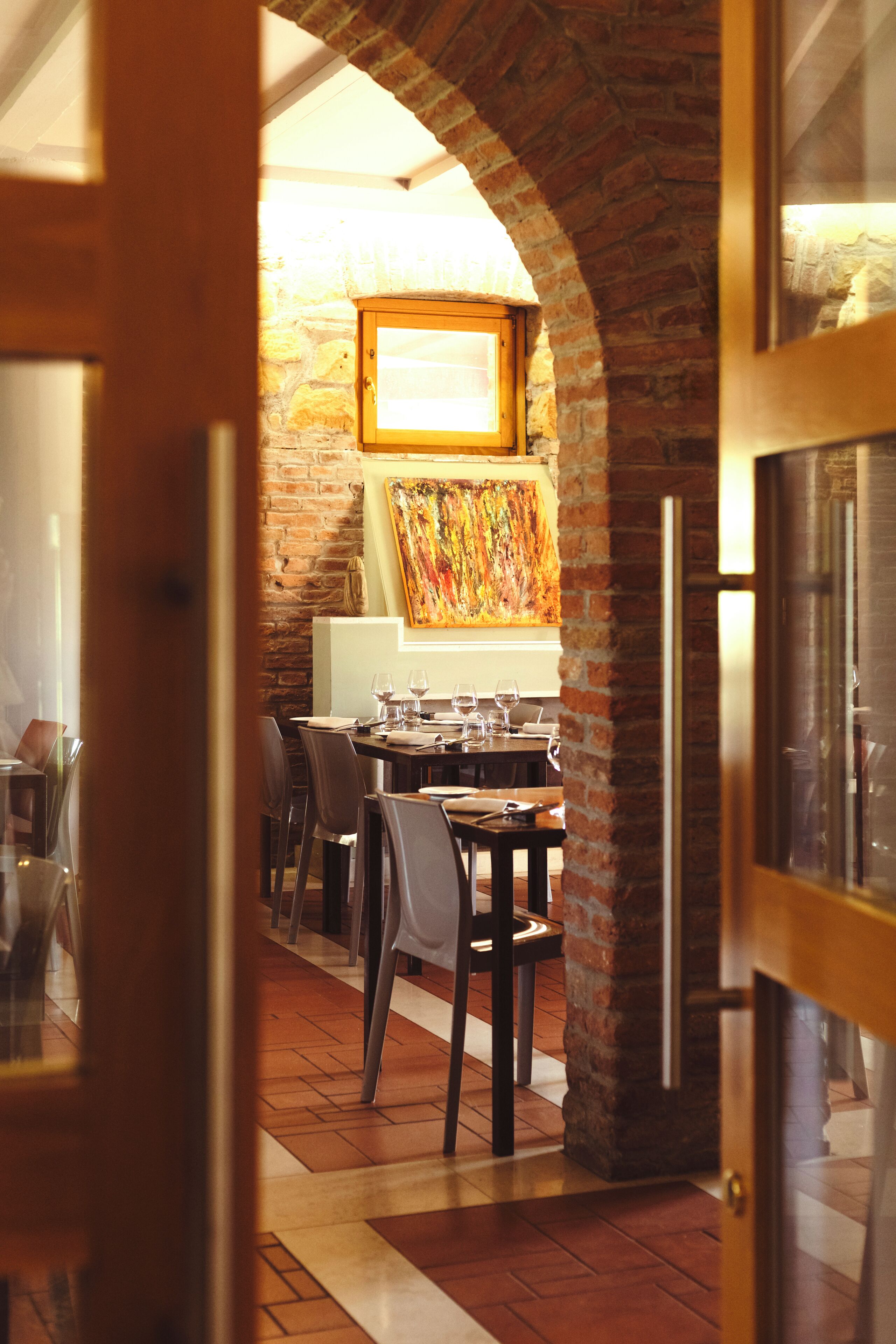 Um restaurante com paredes de tijolo, área de jantar com mesas e cadeiras, e um quadro na parede.