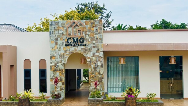 A entrada do CMG Hotels Tarime, com um arco de pedra e plantas em vasos.