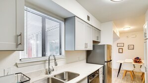 Uma cozinha moderna com pia dupla, eletrodomésticos de aço inoxidável e um espaço de refeições com mesa e cadeiras.