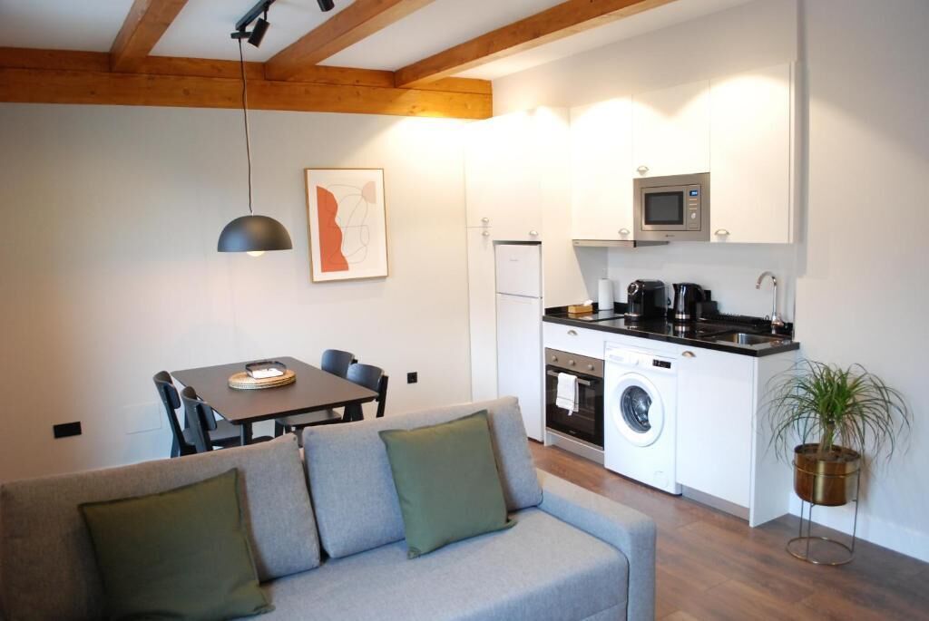 Cozinha compacta com máquina de lavar, micro-ondas e cafeteira.