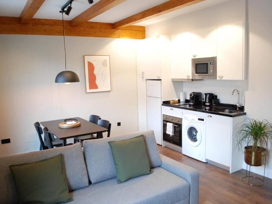 Cozinha compacta com máquina de lavar, micro-ondas e cafeteira.