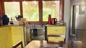 Cozinha com armários amarelos, uma geladeira de aço inoxidável e uma mesa de madeira com um jogo americano.