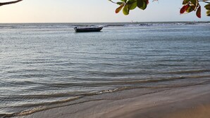 Uma praia com um barco na água e céu claro.