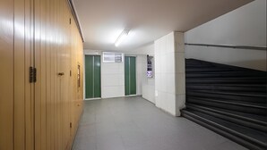 Um corredor com armários, escadas e uma porta com aviso.