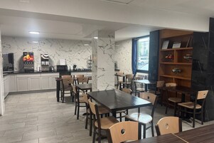 Uma área de refeições moderna com paredes de mármore, uma máquina de café e vista para a rua.