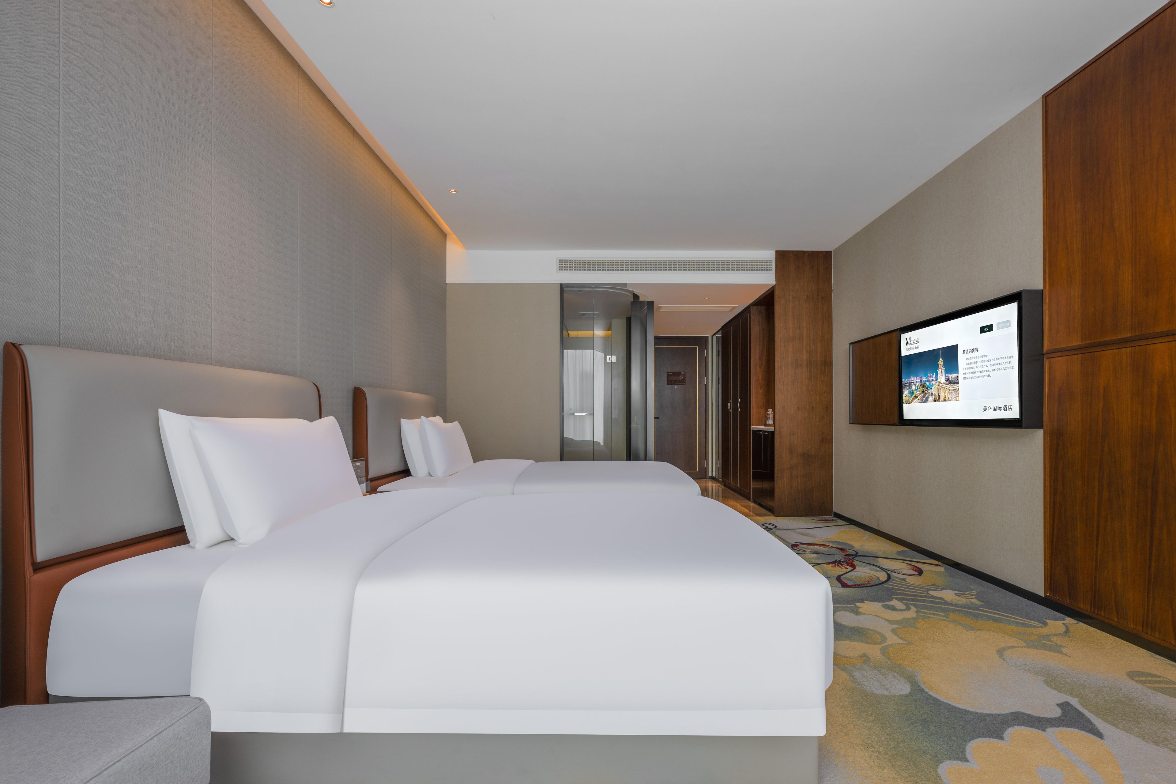 Quarto de hotel moderno com uma cama grande, televisão de tela plana e piso coberto por carpete.