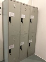 Uma fileira de armários de metal cinza, com compartimentos numerados, cada um com uma fechadura e uma pequena etiqueta.