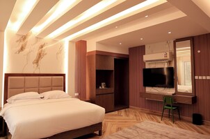 Quarto moderno com uma cama grande, roupeiro embutido e uma televisão.