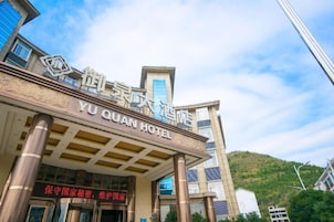 Exterior do Hotel Yu Quan, com entrada visível, colunas imponentes e uma placa.