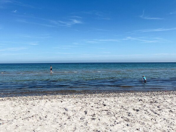 Uma praia com pedras e duas pessoas na água.