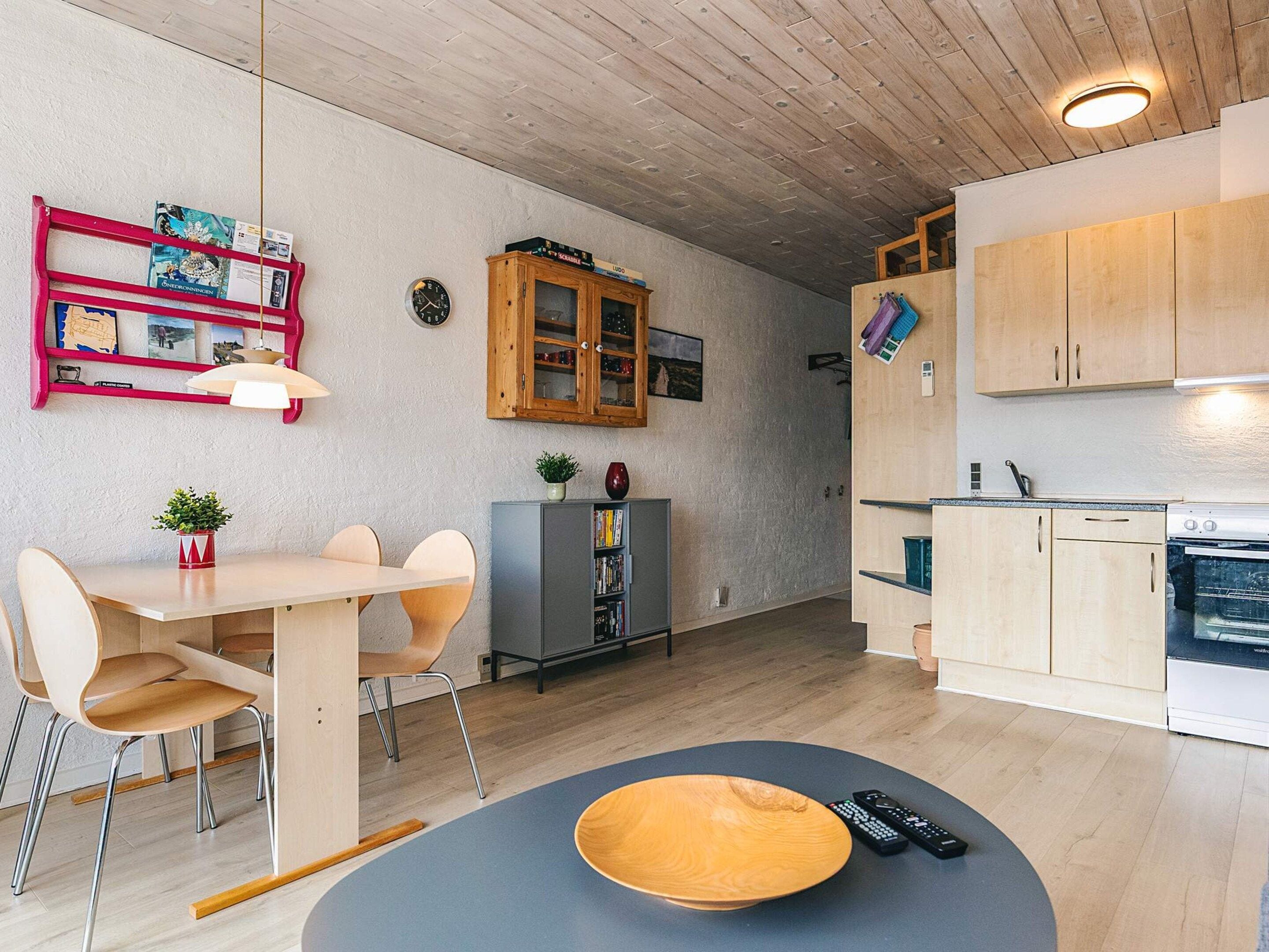 Um espaço de estar compacto com área de refeições, cozinha e um pequeno espaço para sentar.