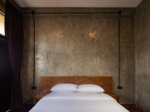 Quarto com cabeceira de madeira, cama com roupa de cama branca e uma janela grande com cortinas.