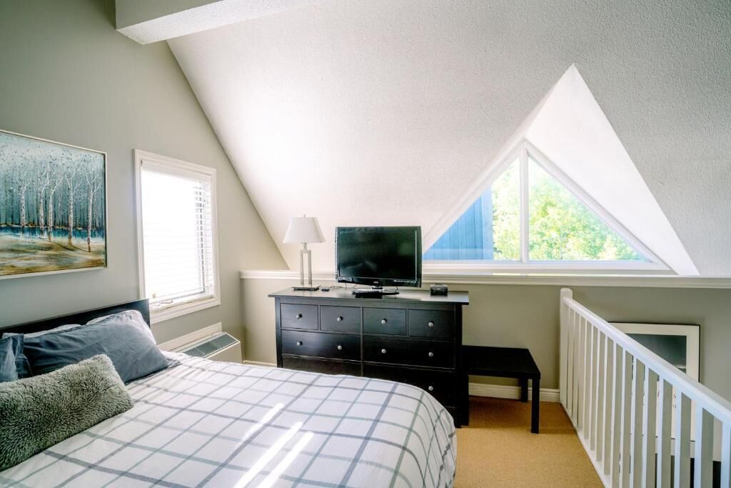 Quarto com cama, penteadeira, televisão e janela.