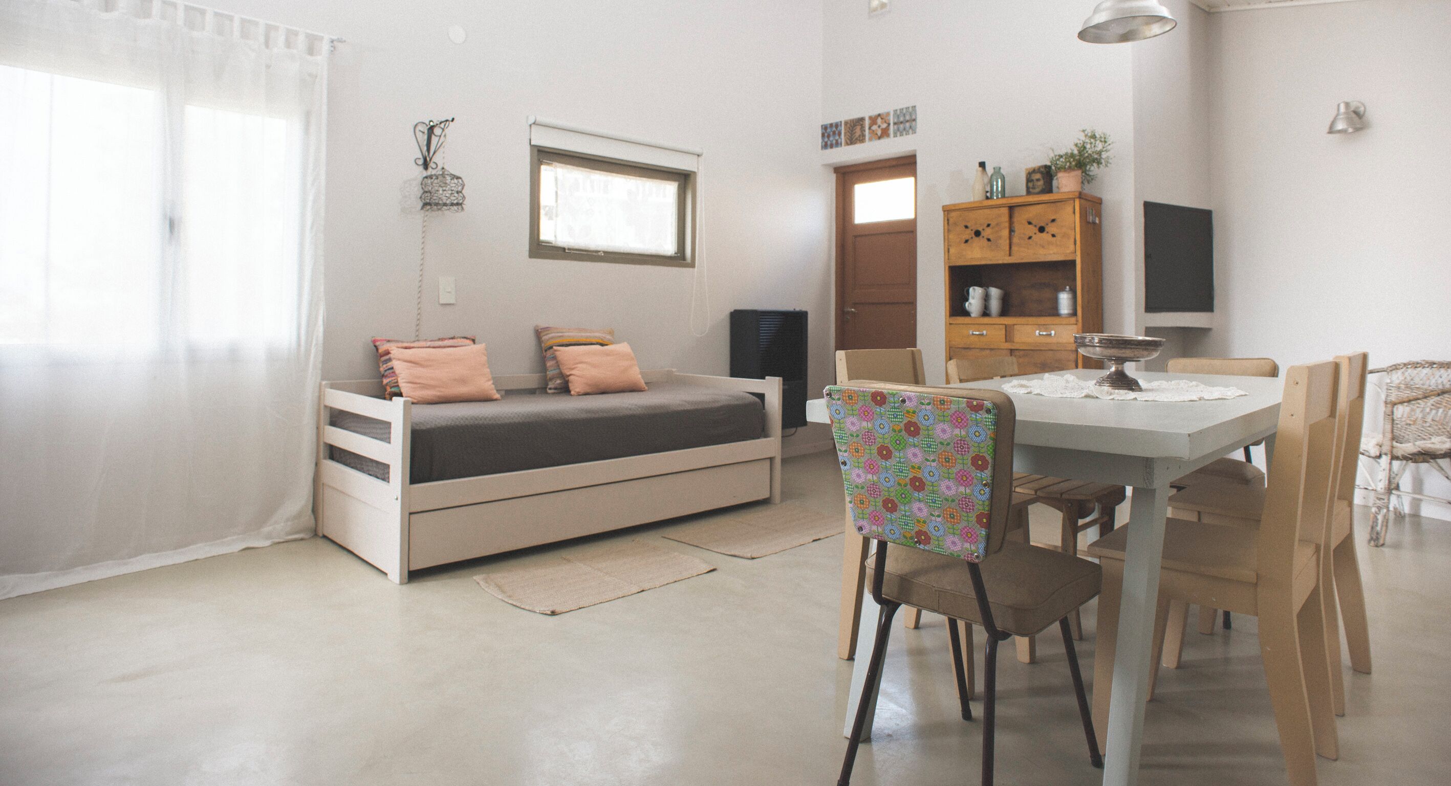 Um espaço compacto com sofá-cama, mesa de jantar, cadeiras e armário.