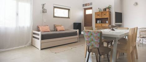 Um espaço compacto com sofá-cama, mesa de jantar, cadeiras e armário.