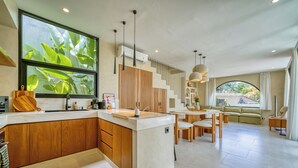 Uma cozinha moderna com armários de madeira, uma ilha central e uma área de jantar com sofá e cadeiras.