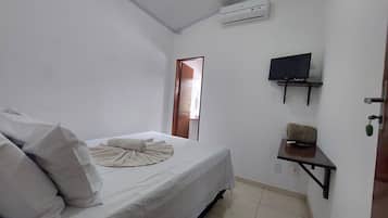 Quarto com cama, televisão em móvel e ar condicionado na parede.