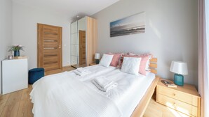 Quarto com cama grande, mesas de cabeceira, guarda-roupa e espelho.
