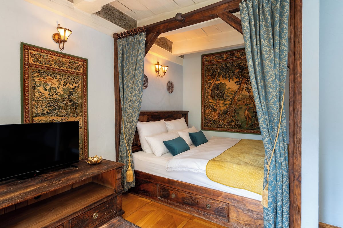 Quarto com cama de madeira, televisão sobre suporte de madeira e decoração de parede.