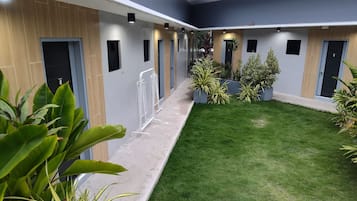 Interior moderno de hotel com um pátio central, várias portas e plantas em vasos.