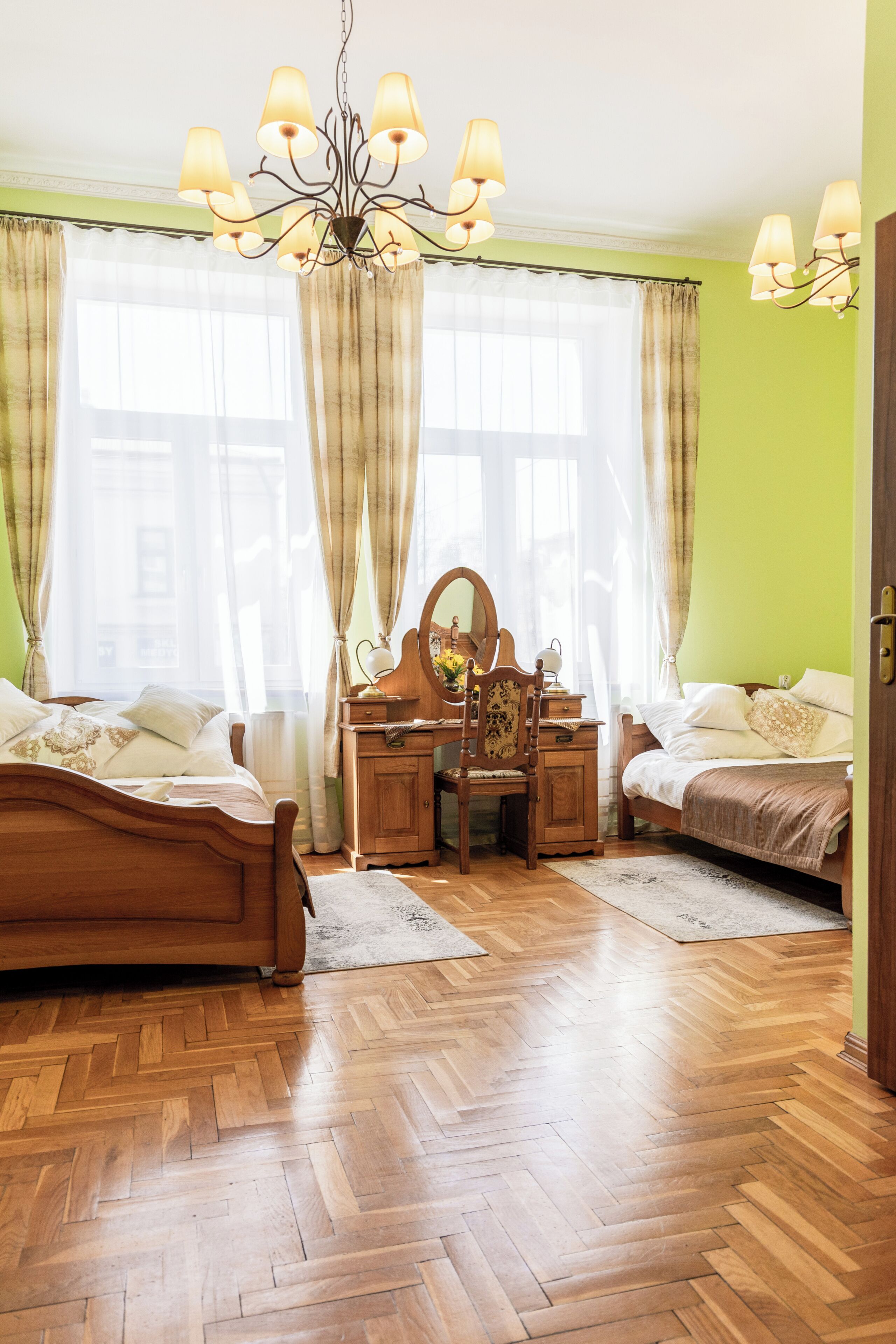 Quarto com cama de madeira, escrivaninha de madeira com espelho e um candelabro.