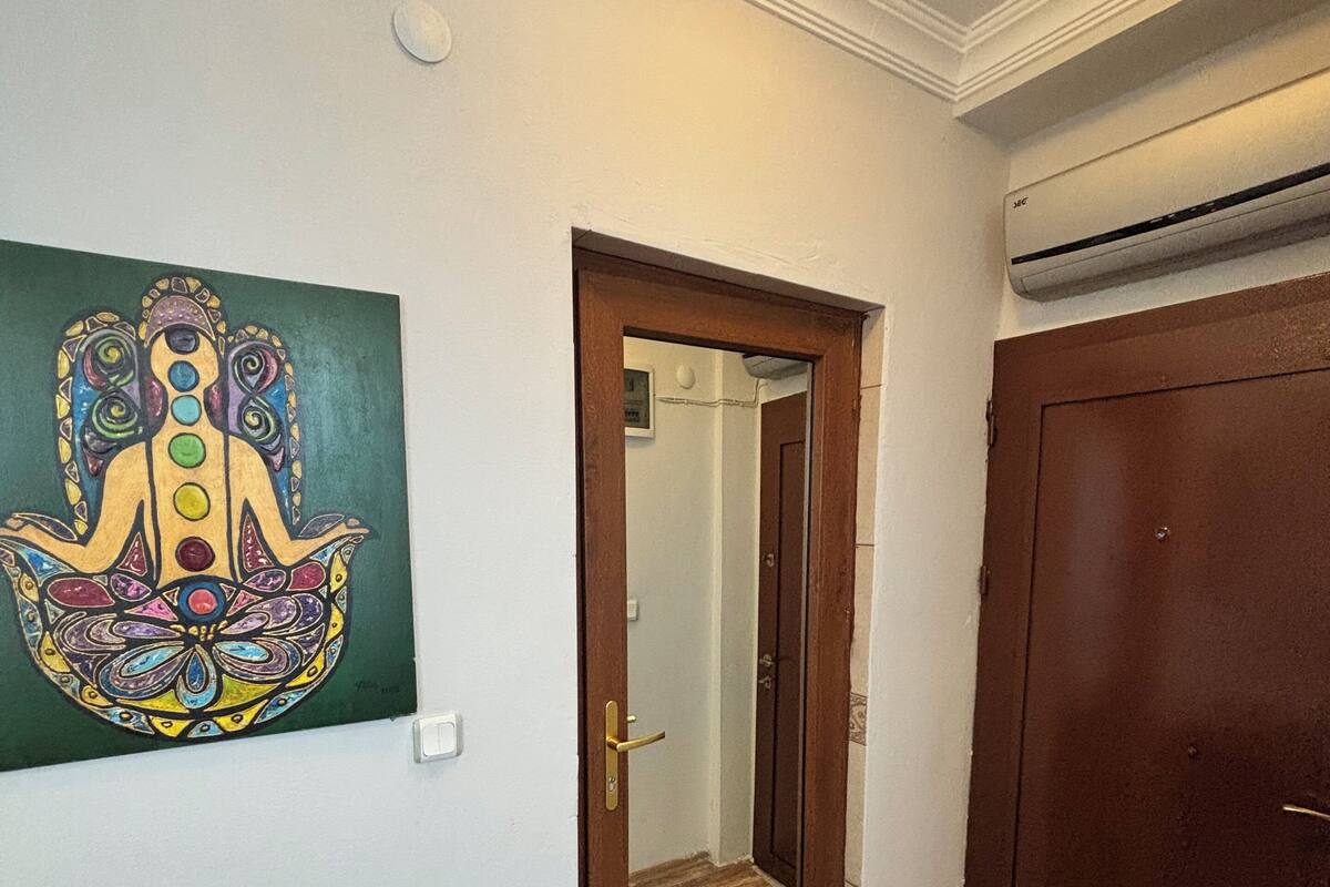 Um corredor com um banco de madeira, uma porta e um ar-condicionado fixado na parede.