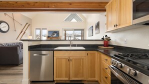 Uma cozinha moderna com armários de madeira, eletrodomésticos de aço inoxidável e uma ampla janela com vista para as montanhas.