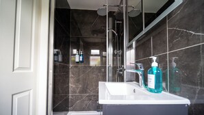 Uma casa de banho moderna com uma pia branca, um espelho e uma área de duche.
