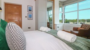 Quarto de hotel com cama, cadeira, janela e vista, além de uma porta.