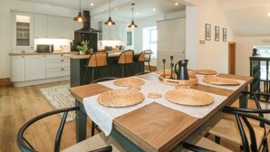 Uma cozinha moderna com armários brancos, uma ilha central e iluminação pendente.