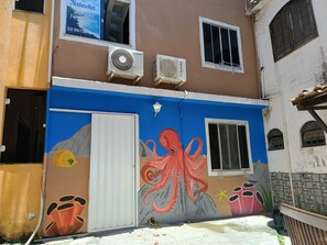 Edifício com um mural de um polvo, aparelhos de ar condicionado e uma placa de identificação de empresa.