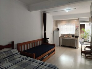 Espaço compacto para viver, incluindo cama, sofá, cozinha compacta e área de refeições.